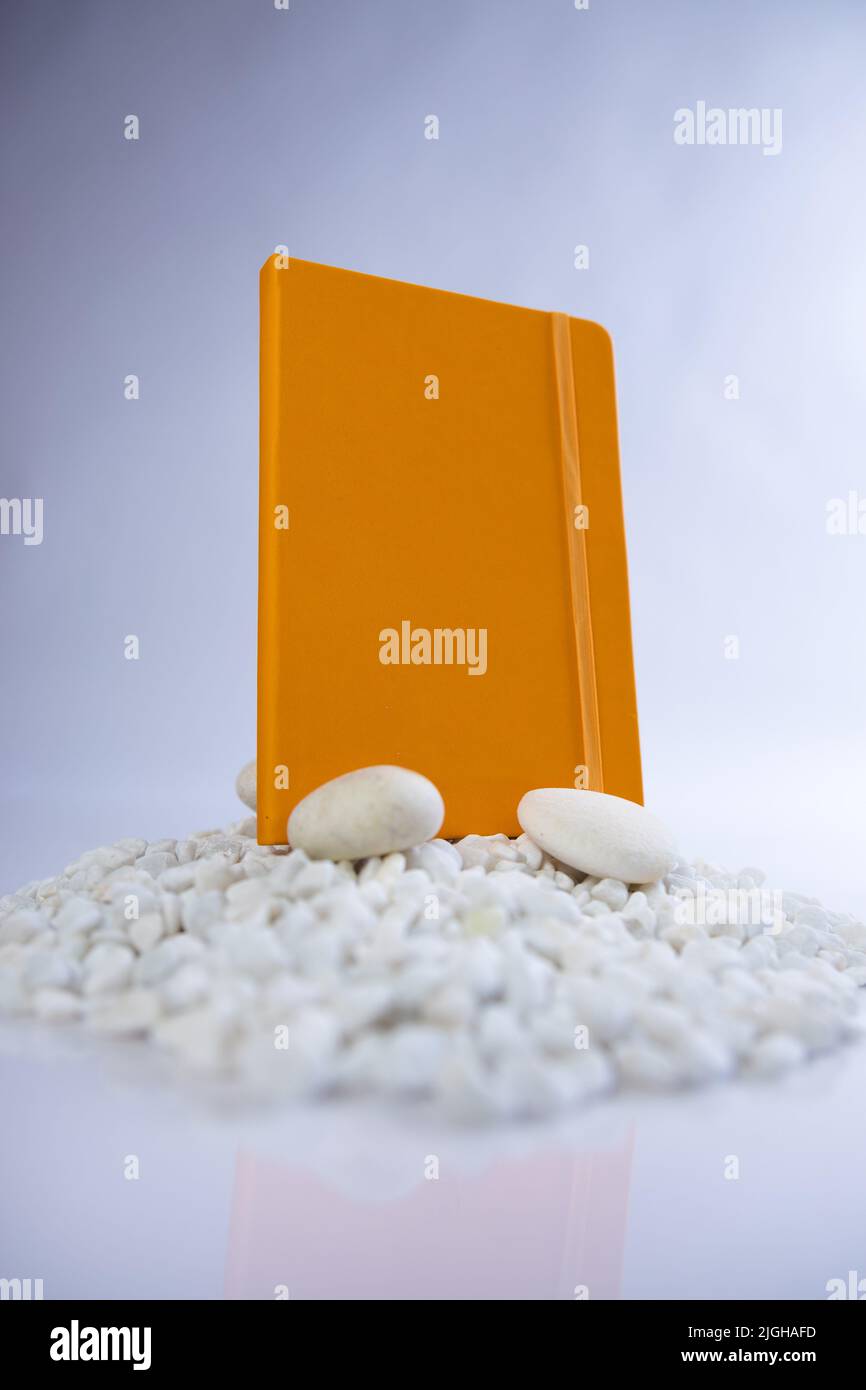 Yellow notebook on a mountain stack of white rocks. Beautiful studio ...