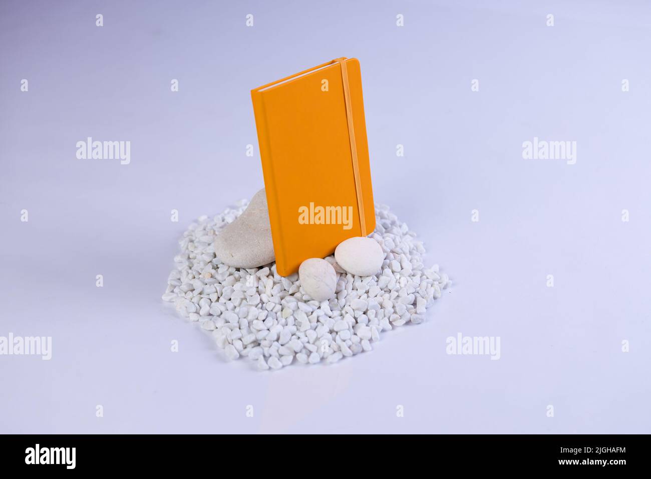 Yellow notebook on a mountain stack of white rocks. Beautiful studio ...