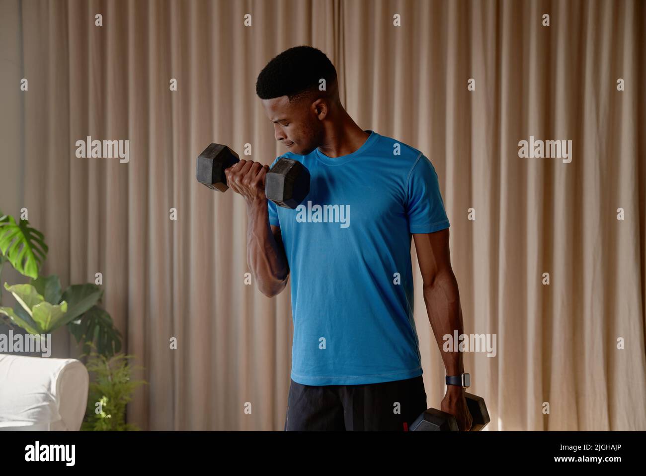 Front view of a Black African American young male exercising at home in ...