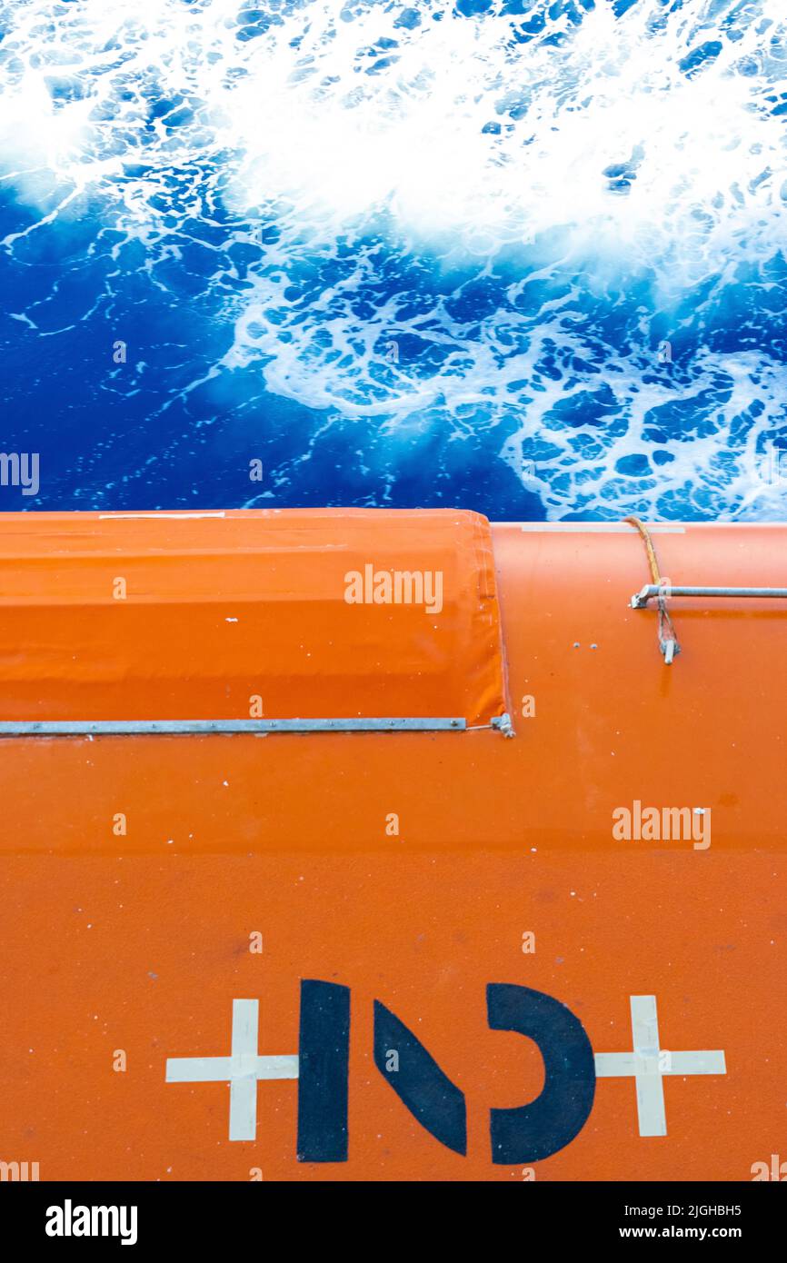 A top view of an orange boat with number "2" against blue ocean waves ...