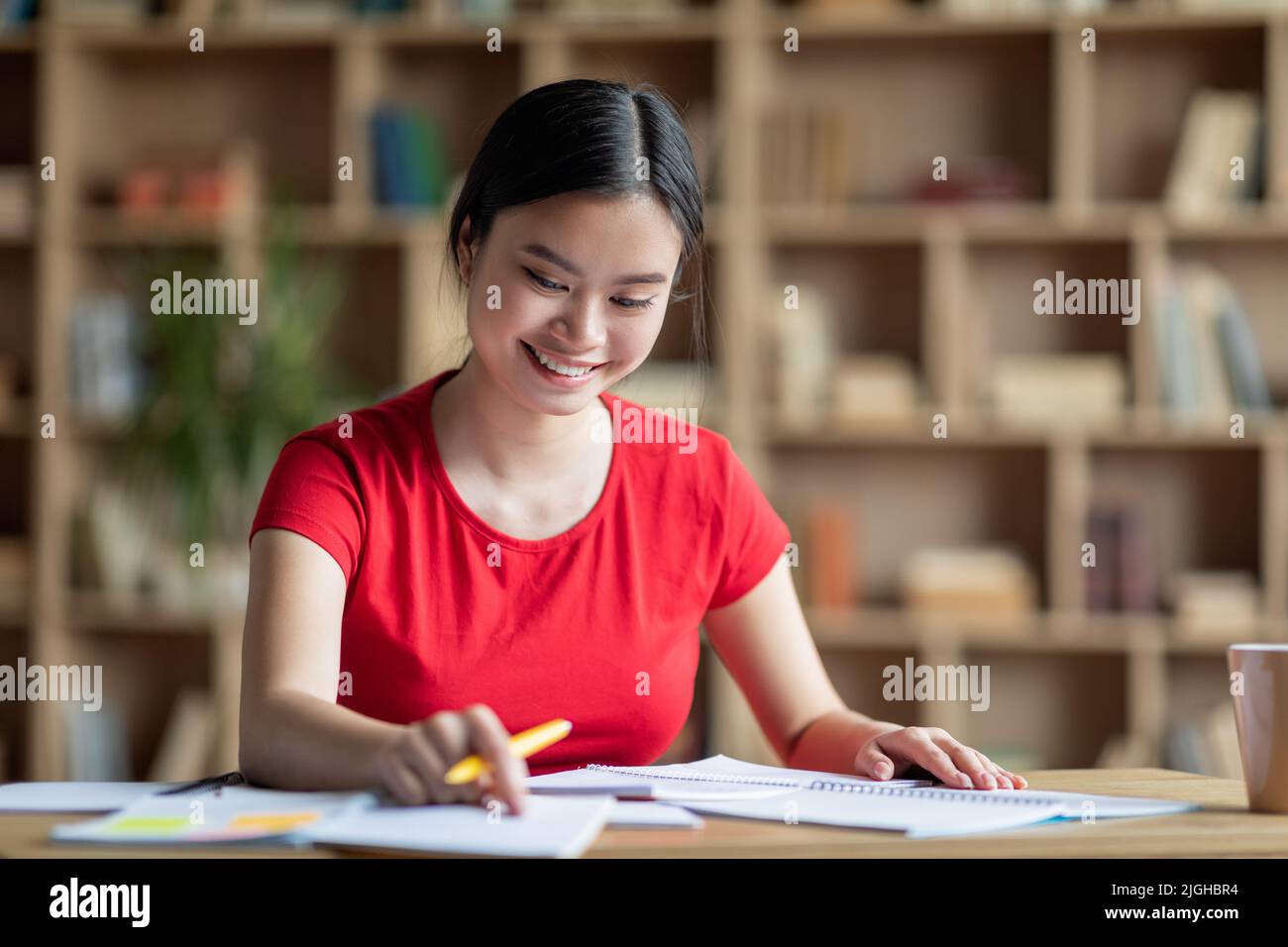 Glad cheerful pretty smart young asian lady student study at table ...