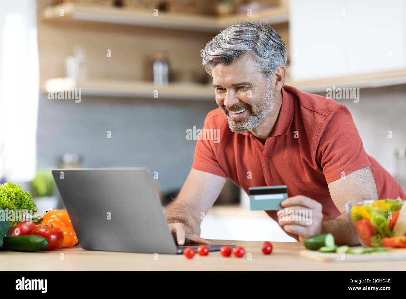 Cheerful middle aged man buying food online, using computer Stock Photo ...
