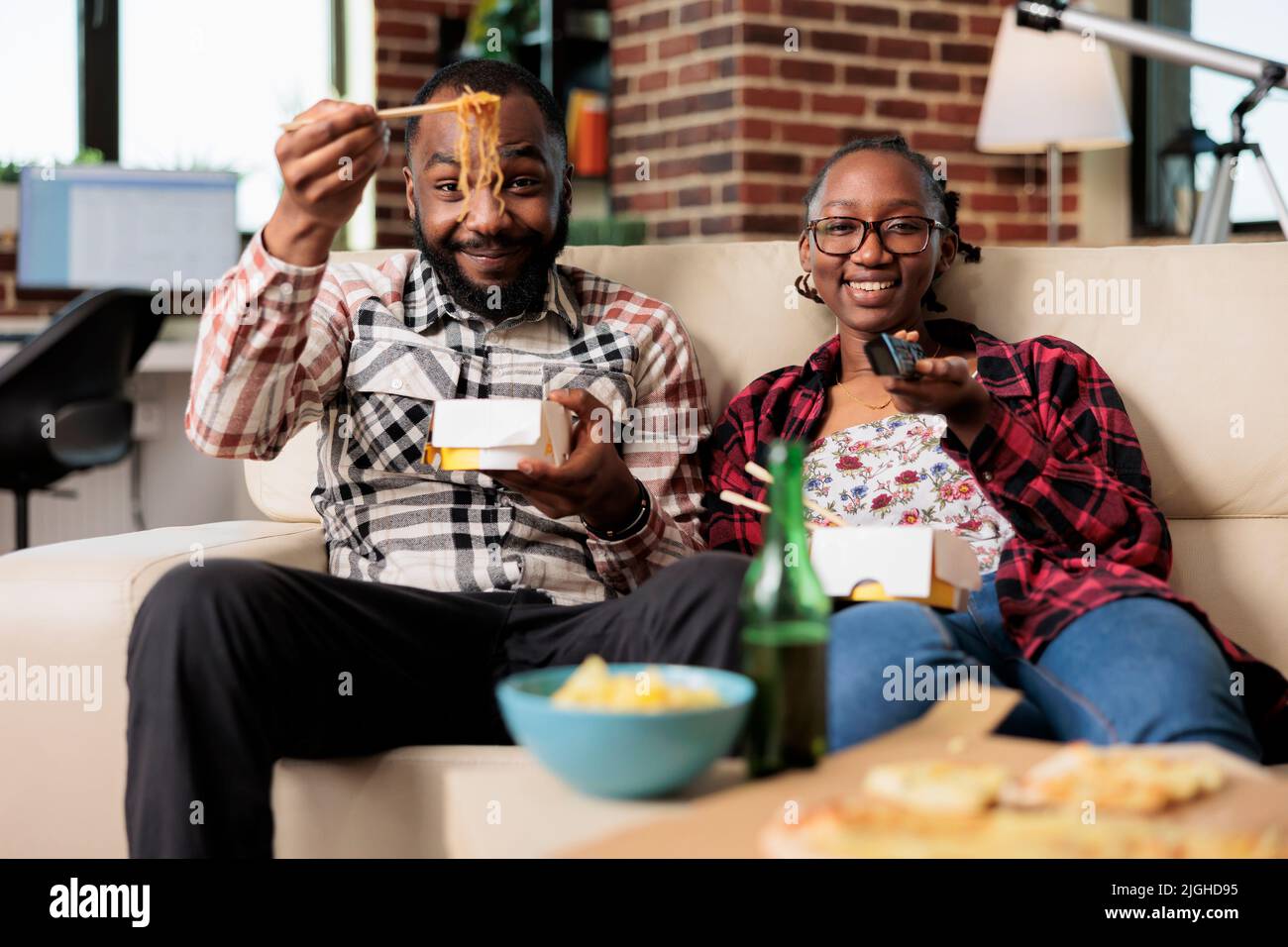 Happy couple watching television and eating noodles meal, switching tv ...