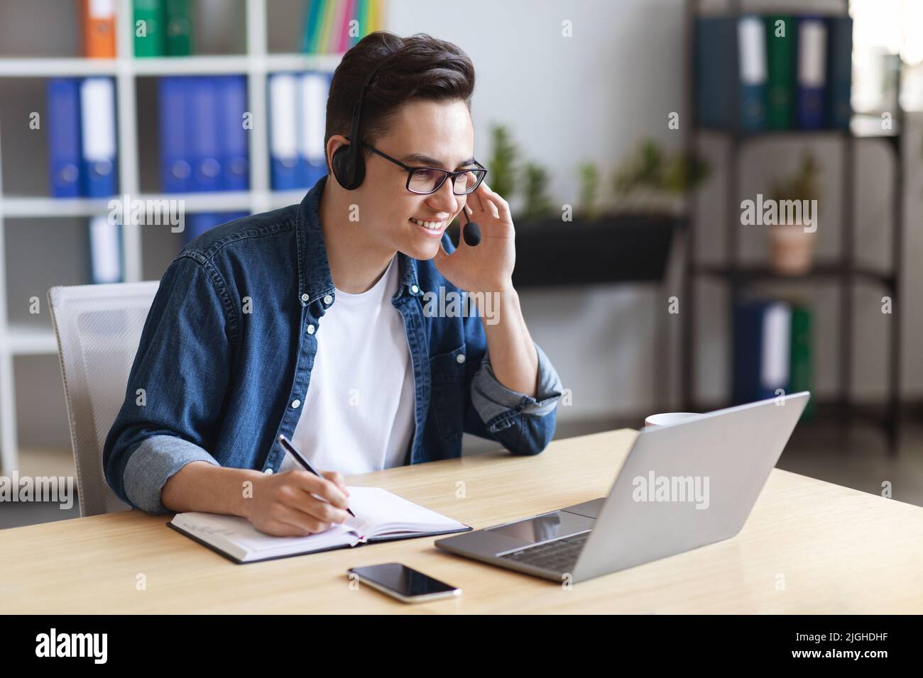 Young Male Office Employee Wearing Headset Watching Online Webinar At ...