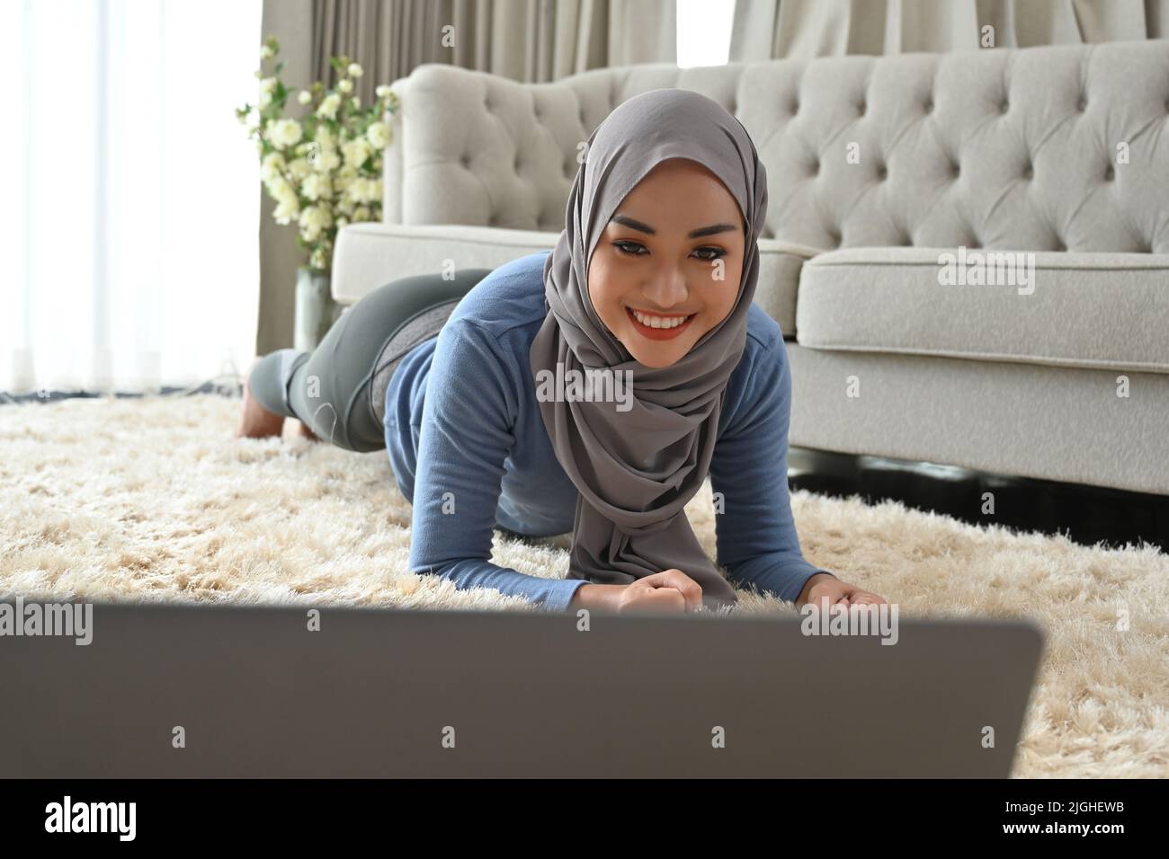 Healthy millennial Asian Muslim woman doing exercise in the living room ...