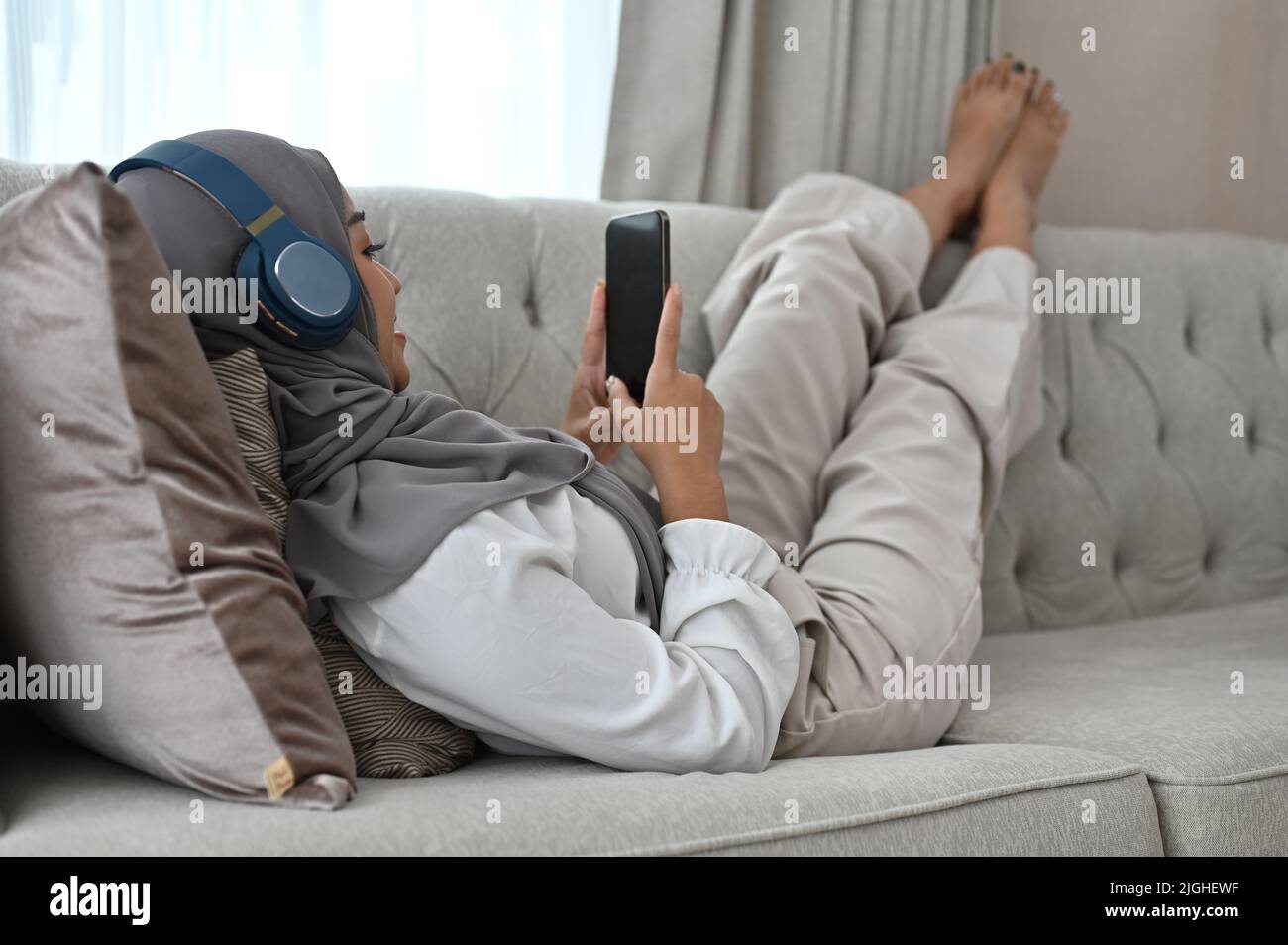 Relaxed and chill young Muslim woman in casual outfit with hijab laying ...