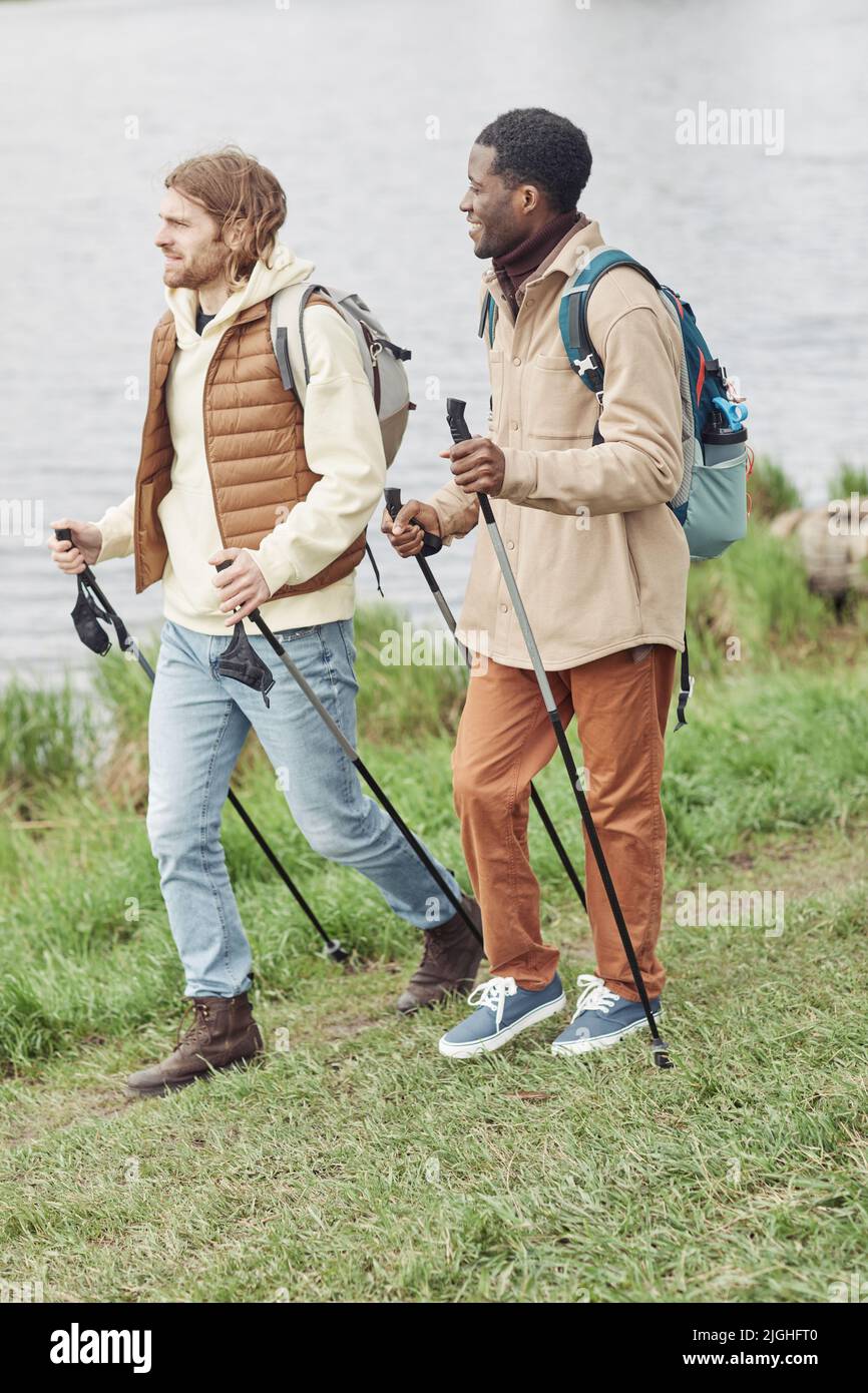 Two young men using sticks during nordic walking in the park outdoors ...