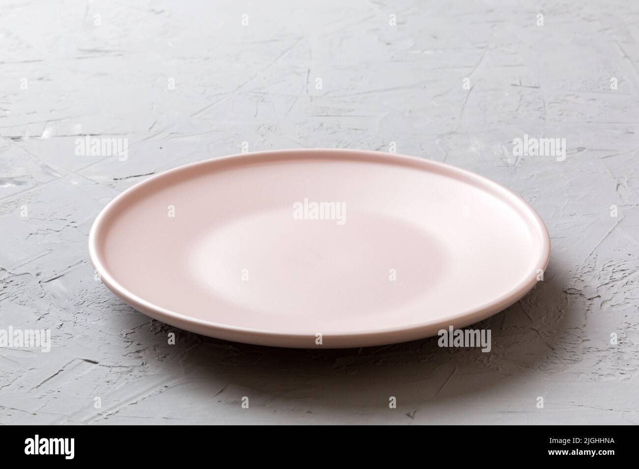 Perspective view of empty pink plate on cement background. Empty space ...