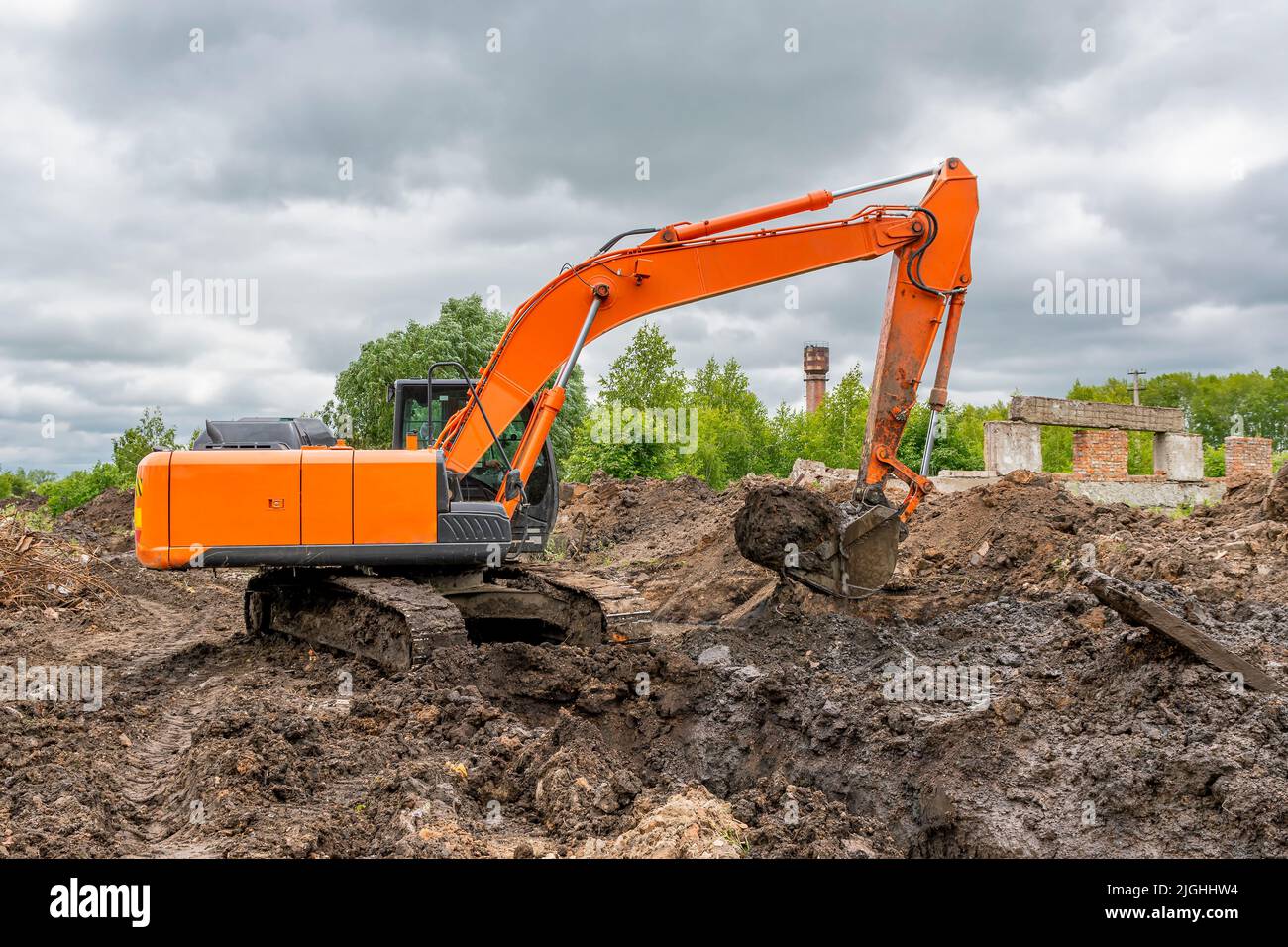 Large orange crawler excavator is excavating (digging a trench) against ...