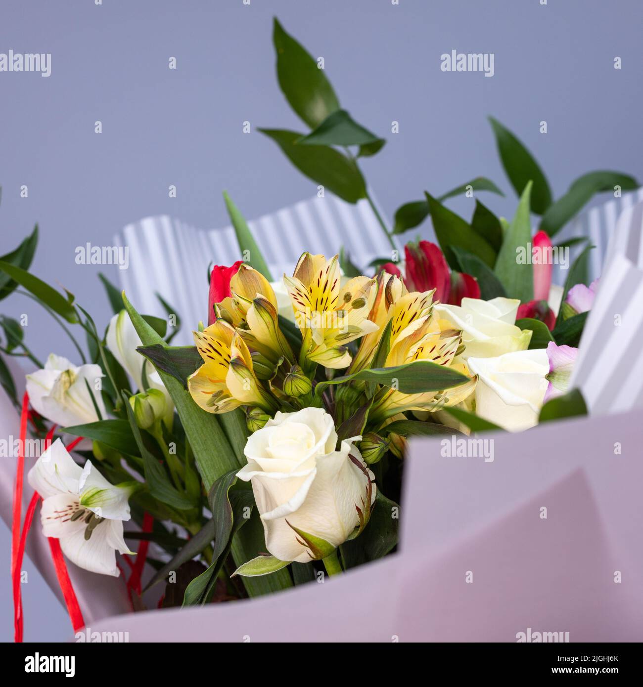 Close up of bright bouquet of colored flowers wrapped in gift paper ...