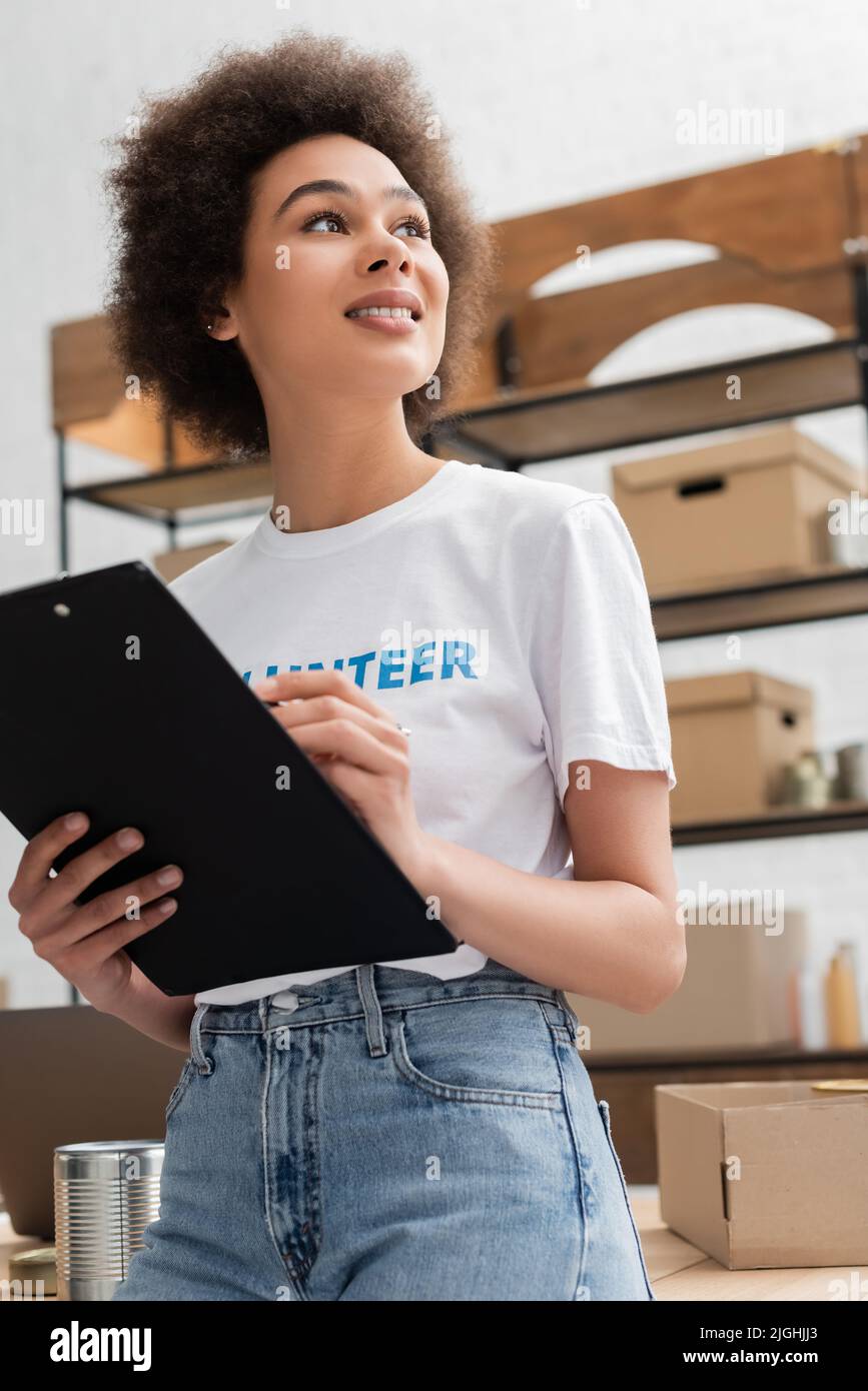 low angle view of smiling african american volunteer with clipboard ...