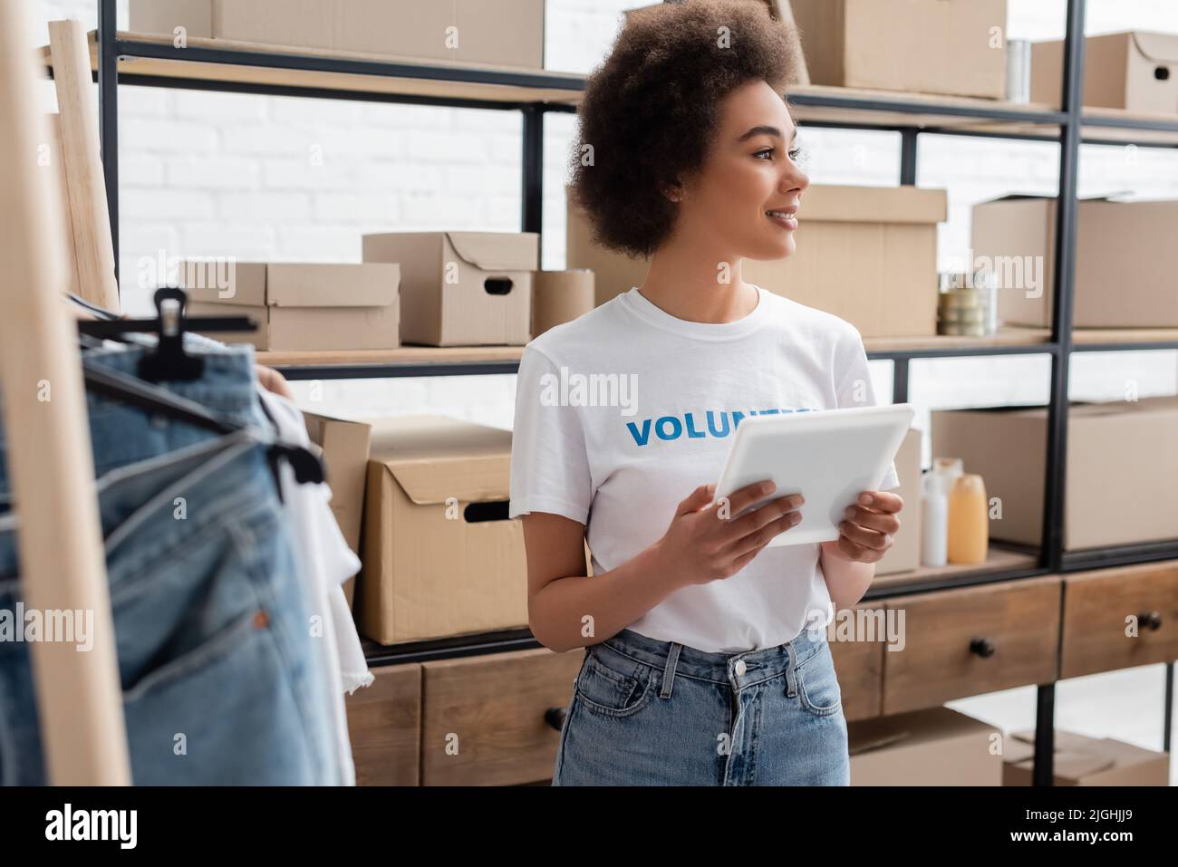 smiling african american volunteer with digital tablet looking away ...