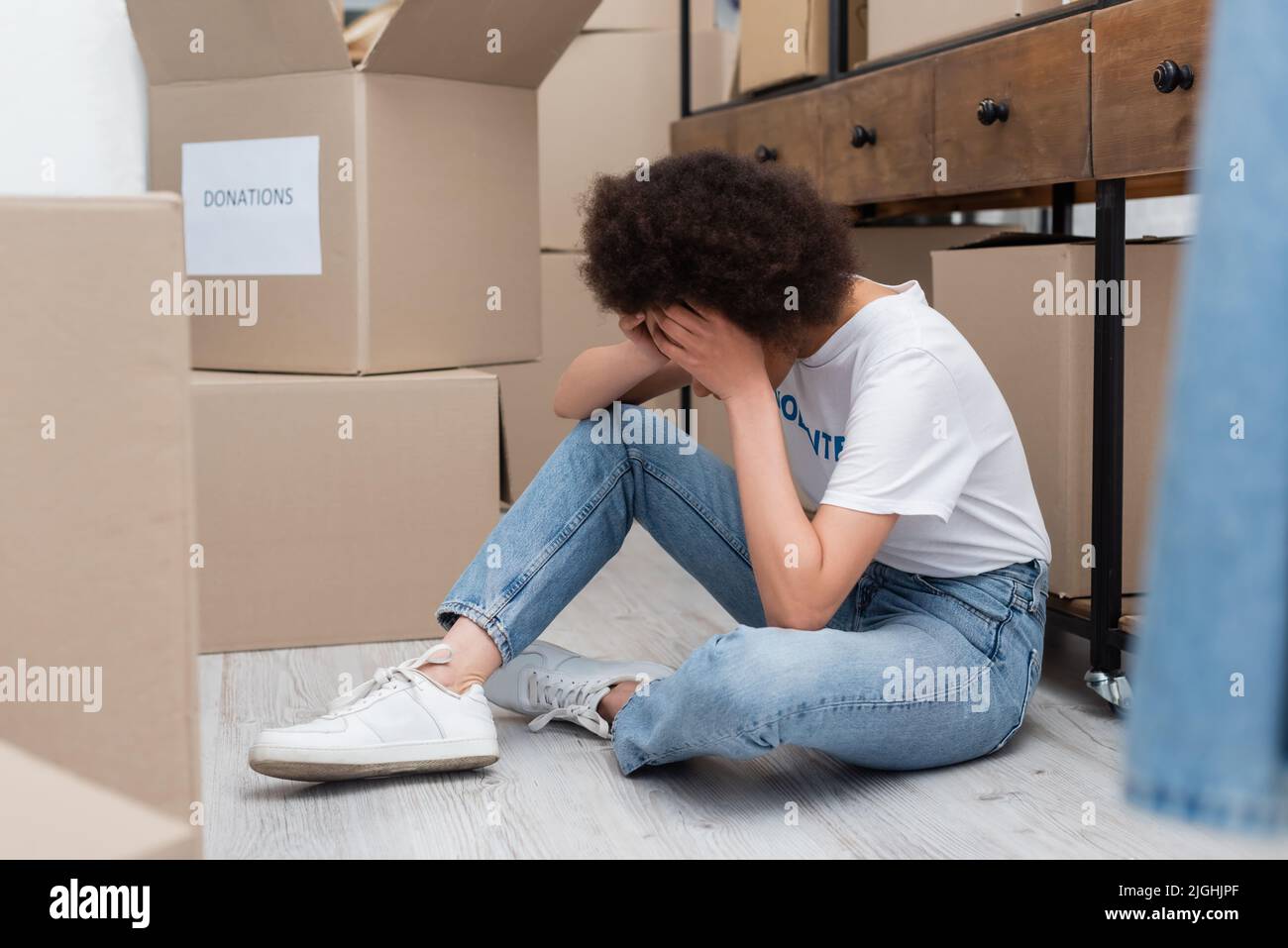 exhausted african american woman obscuring face with hands while ...