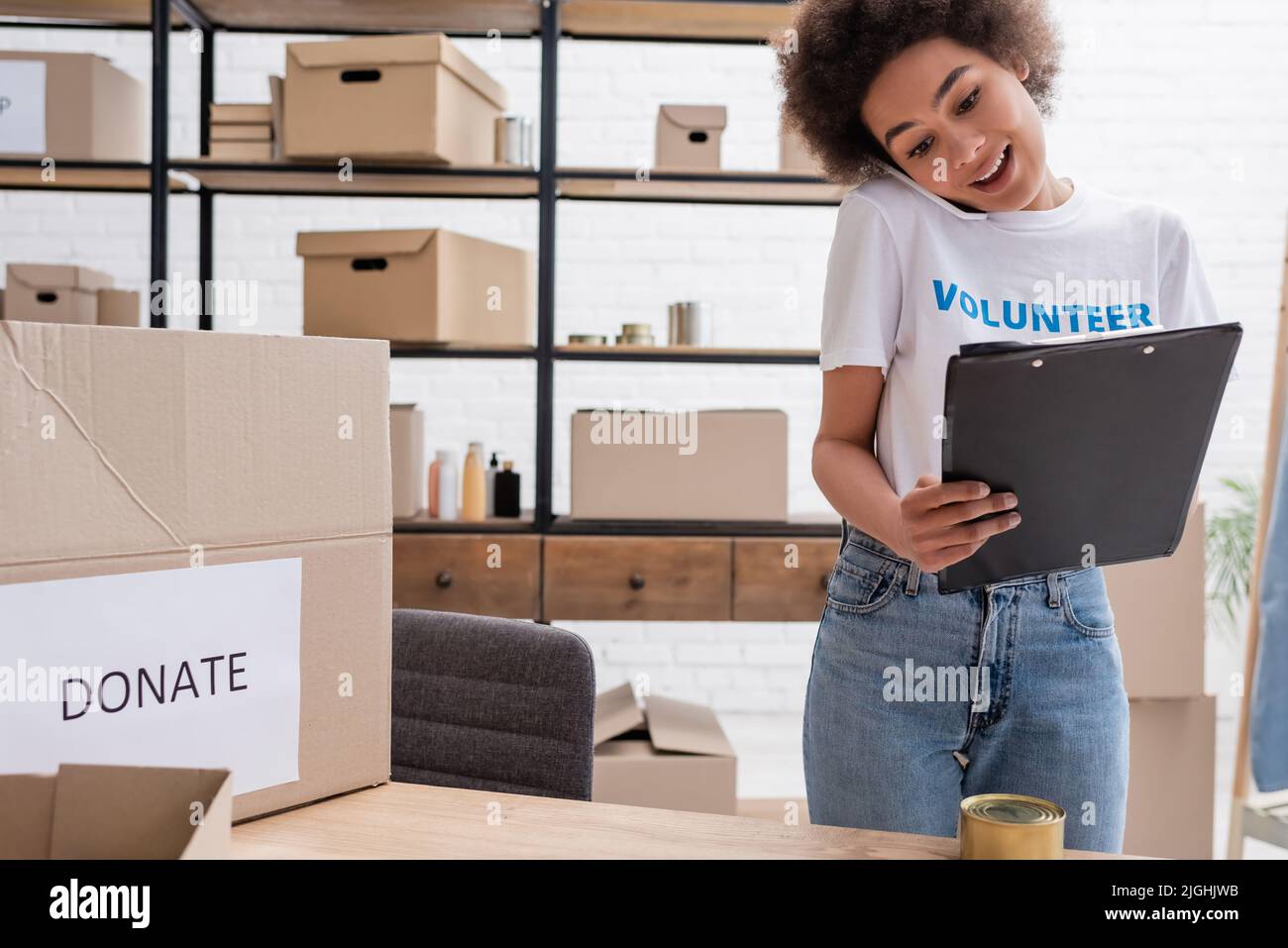 african american volunteer talking on mobile phone near clipboard in ...
