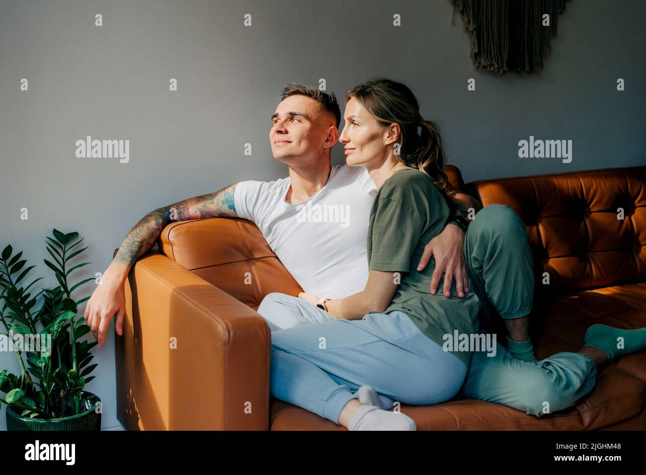 Young couple in love at home on the couch hugging in the sunny bright ...