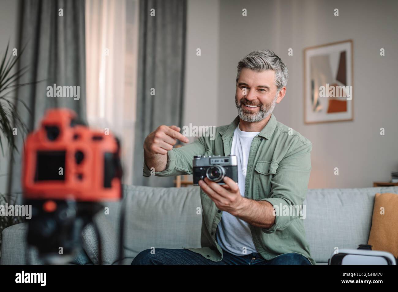 Blogging at home. Happy caucasian senior man with beard shows photo ...