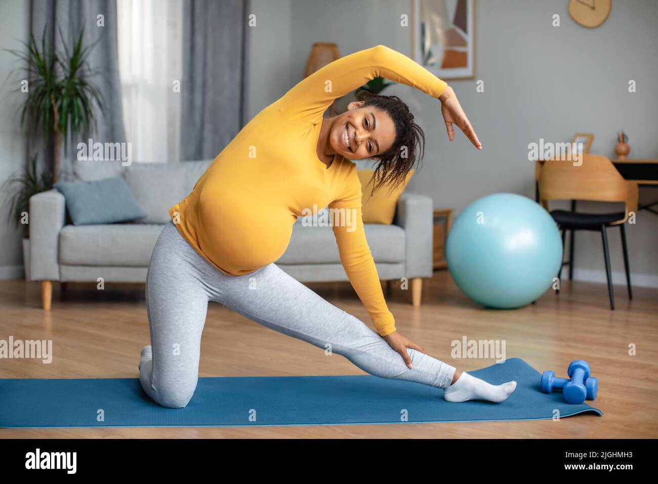 Happy Smiling Young Pregnant Black Female Practicing Yoga Stretching