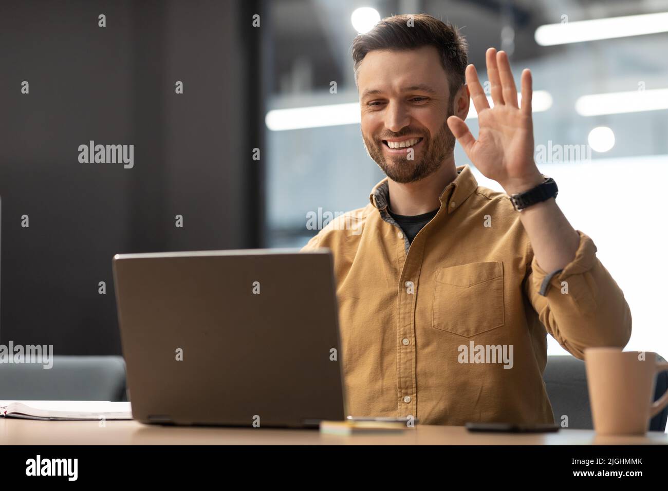 Entrepreneur Waving Hello To Laptop Making Video Call At Workplace ...