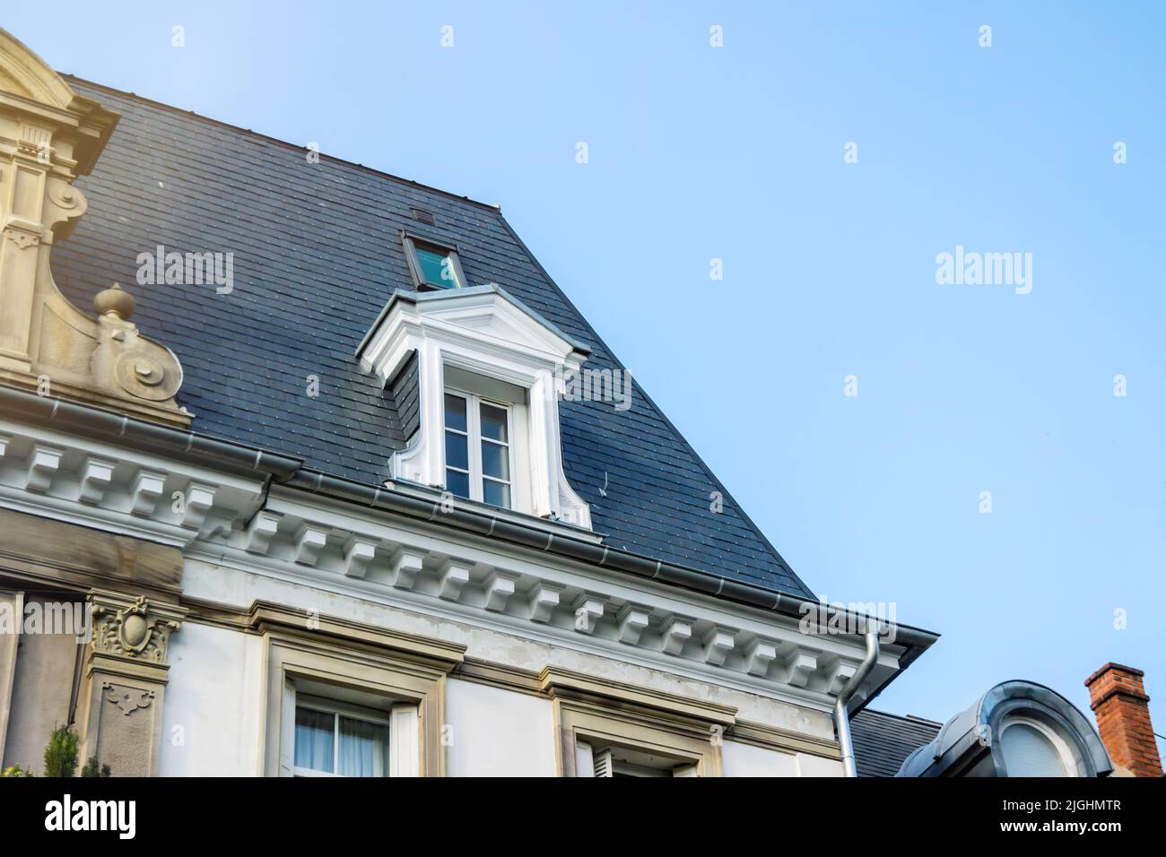 French rooftop with mansard window with blue sky in the background ...
