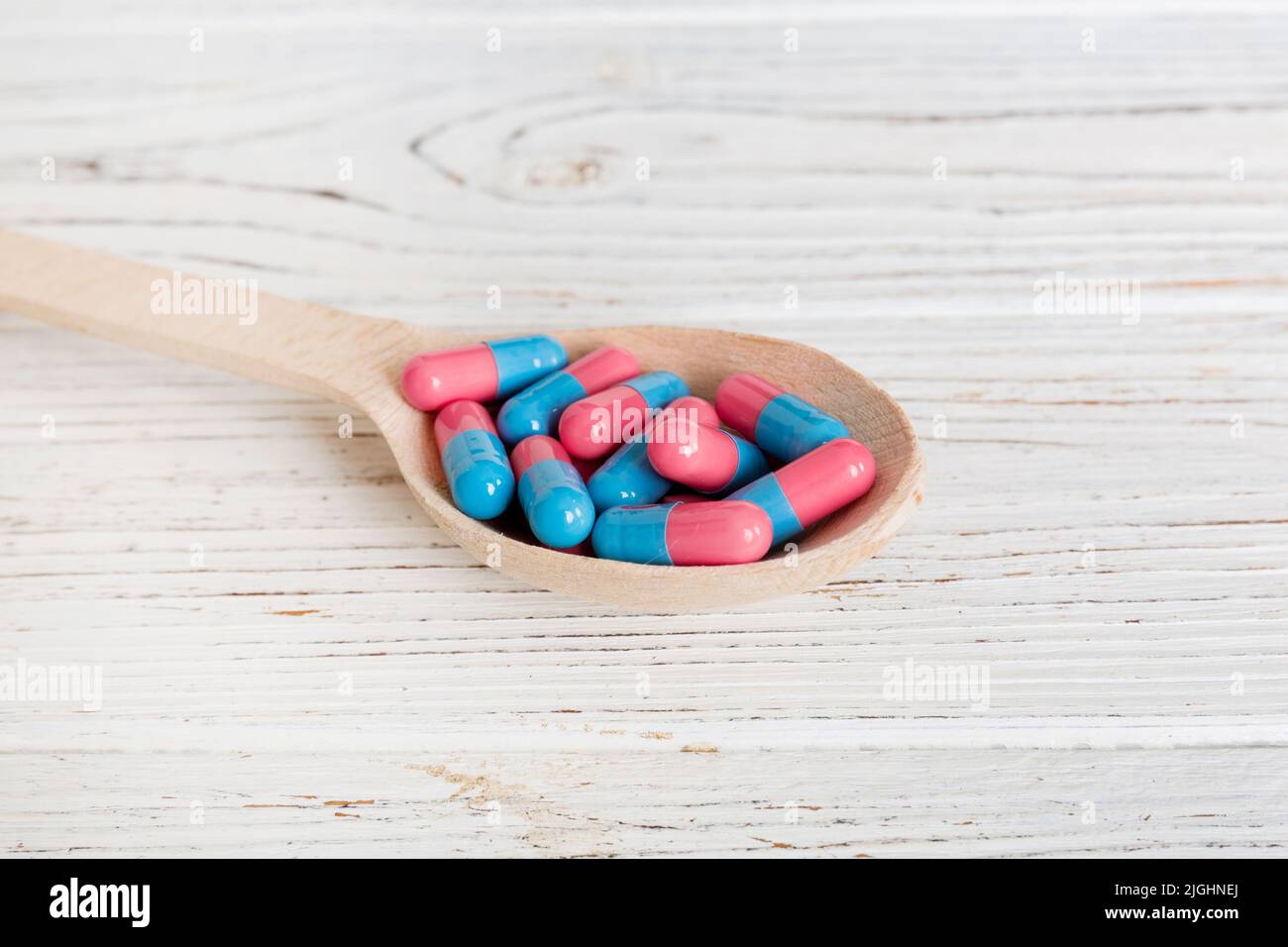 Vitamin capsules in a spoon on a colored background. Pills served as a ...