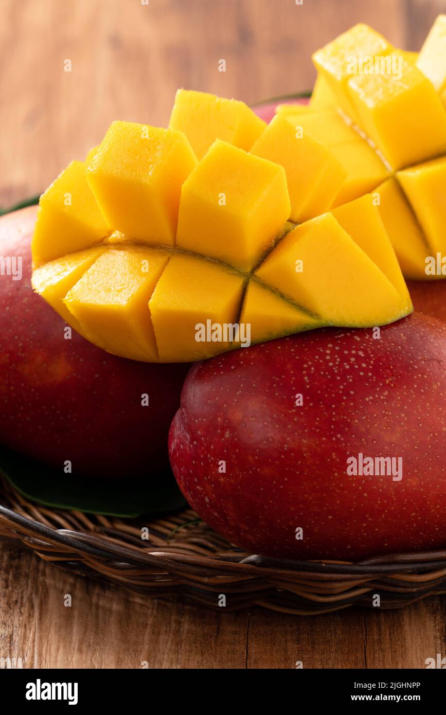 Mango. Close up of fresh ripe mango fruit with leaves over dark wooden ...