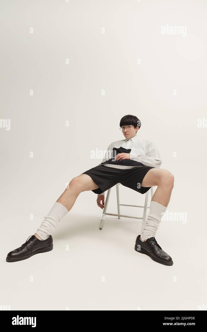 Portrait of stylish young boy sitting on chair, posing isolated on grey ... Portrait of stylish young boy sitting on chair, posing isolated on grey ...