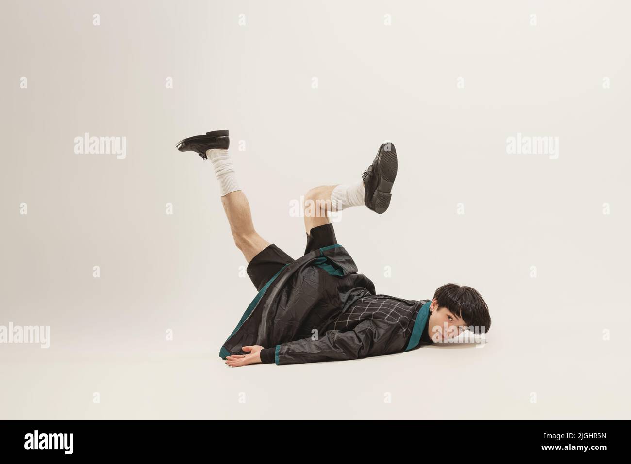 Portrait of stylish young man in black outfit and green coat falling on ...
