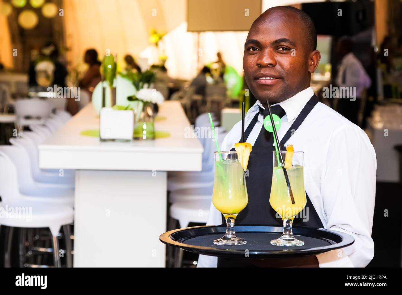 An African waiter holding a tray of welcome drinks at cocktail party ...