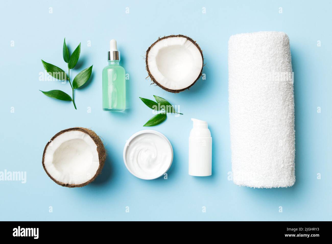 Coconut with jars of coconut oil and cosmetic cream on colored ...