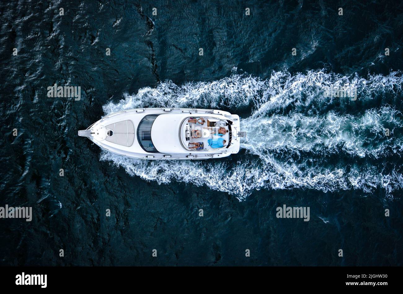 A top view of a motorized boat sailing through water leaving a foamy ...