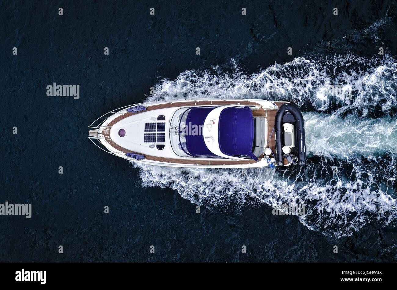 A top view of a motorized boat sailing through water leaving a foamy ...