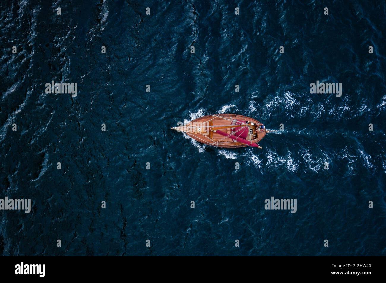 A top view of a motorized boat sailing through water leaving a foamy ...