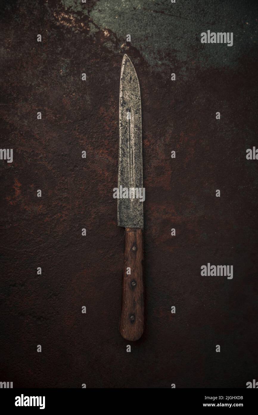 top view of carbon steel blade knife with wooden handle on top of rusty ...