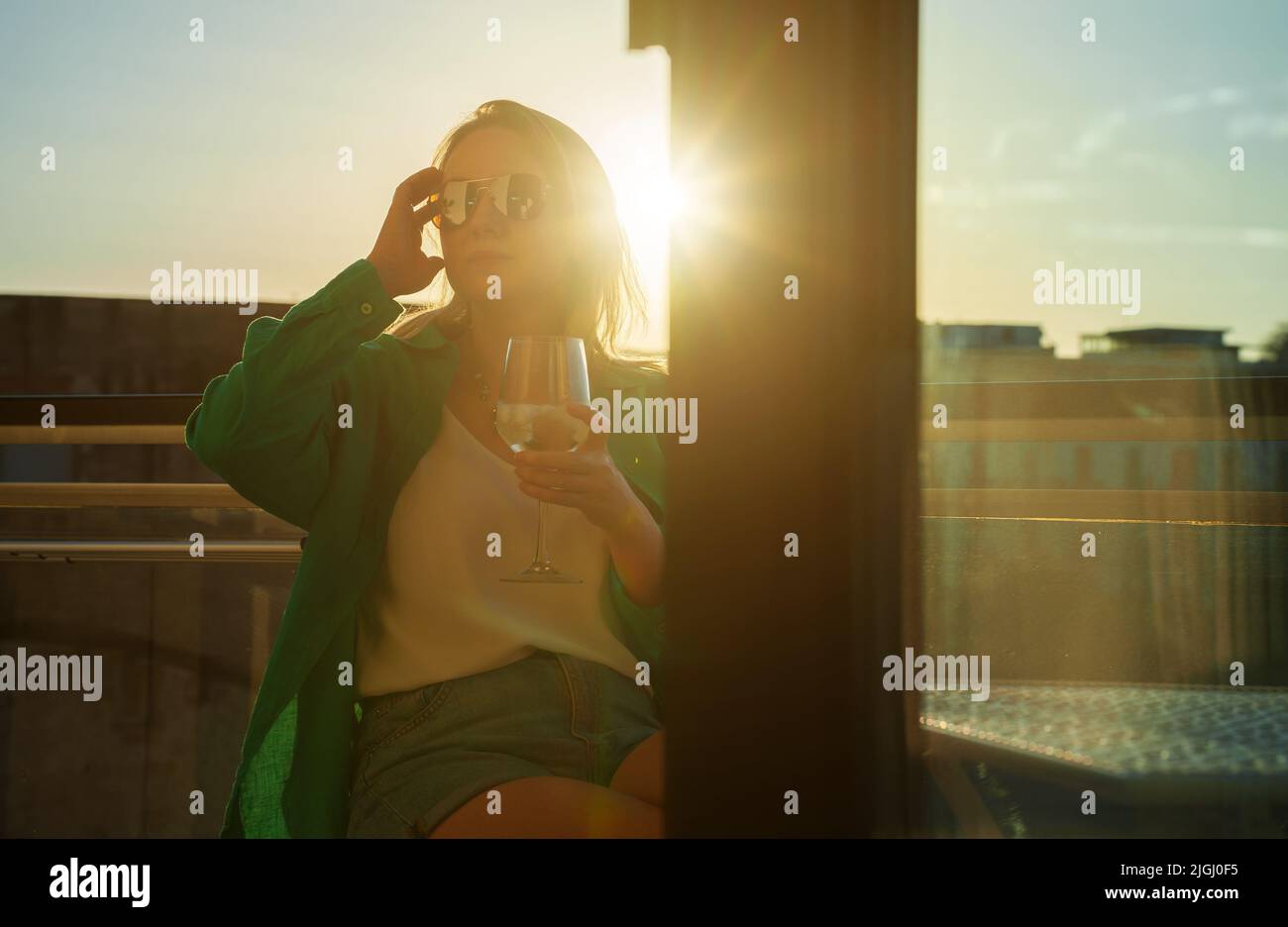 Woman with white wine enjoys the sunset on her balcony Stock Photo - Alamy