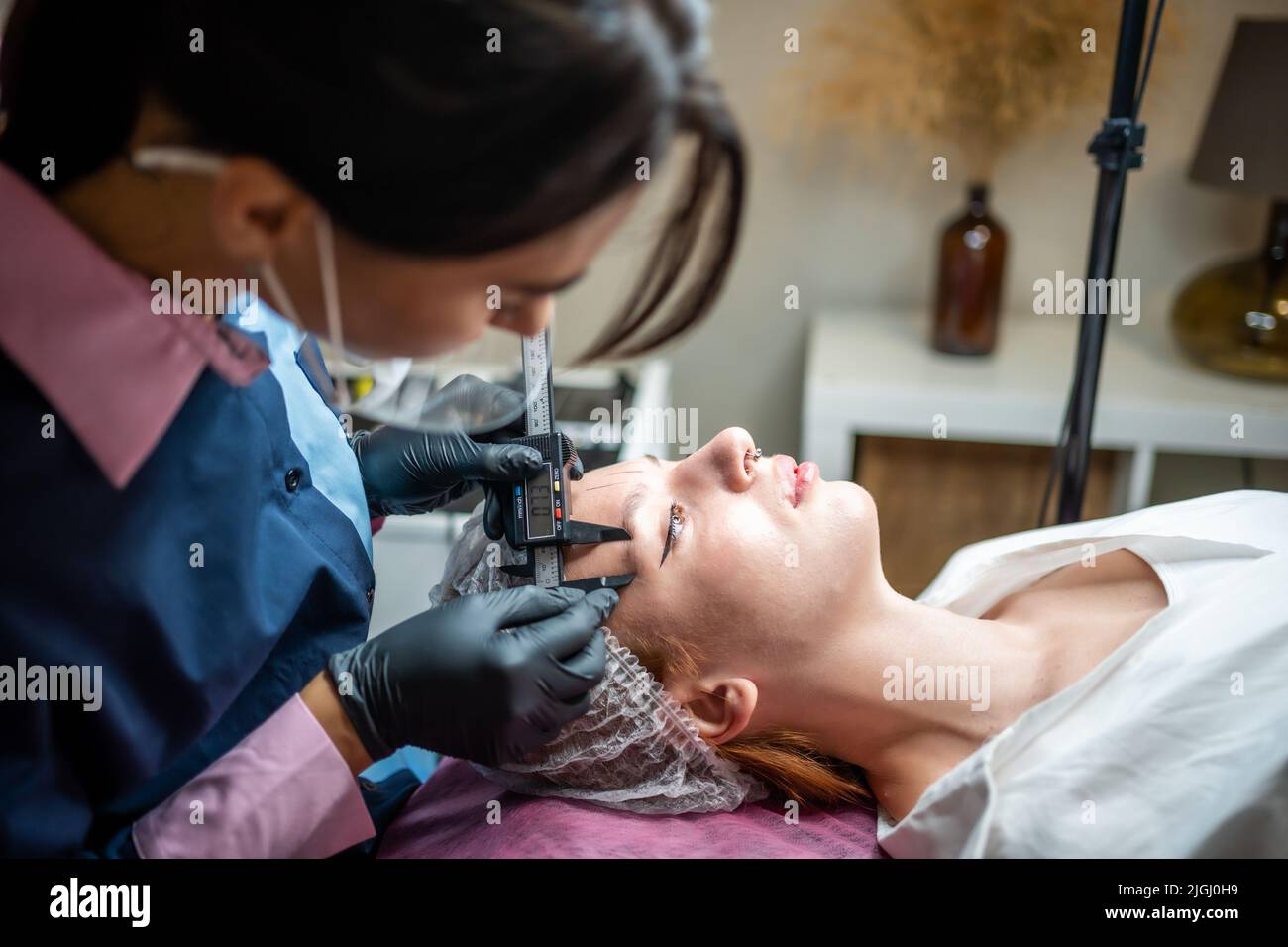 Beauty master measuring eyebrows with calipers before permanent makeup ...