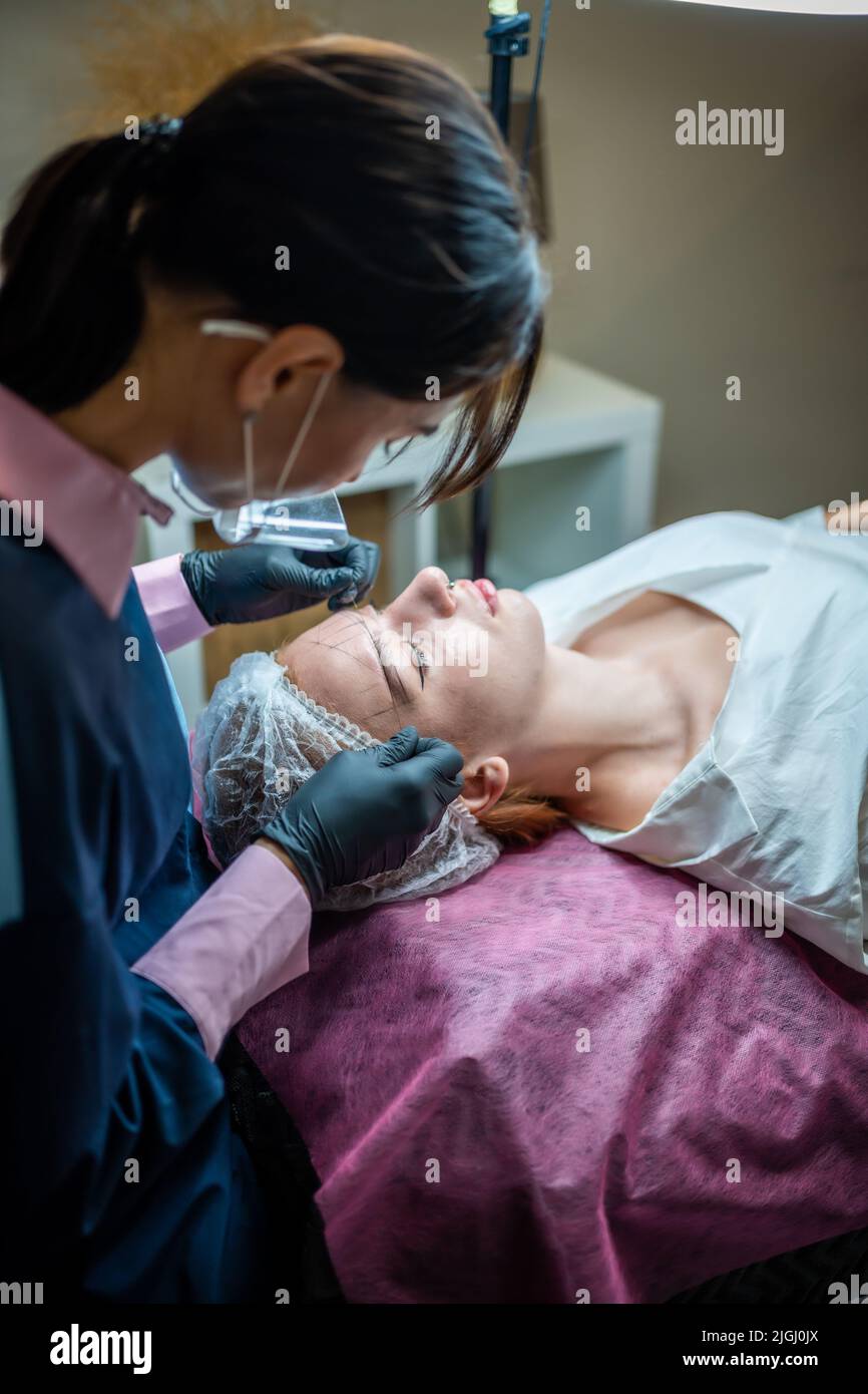 Permanent makeup cosmetologist master takes measurements for the new ...