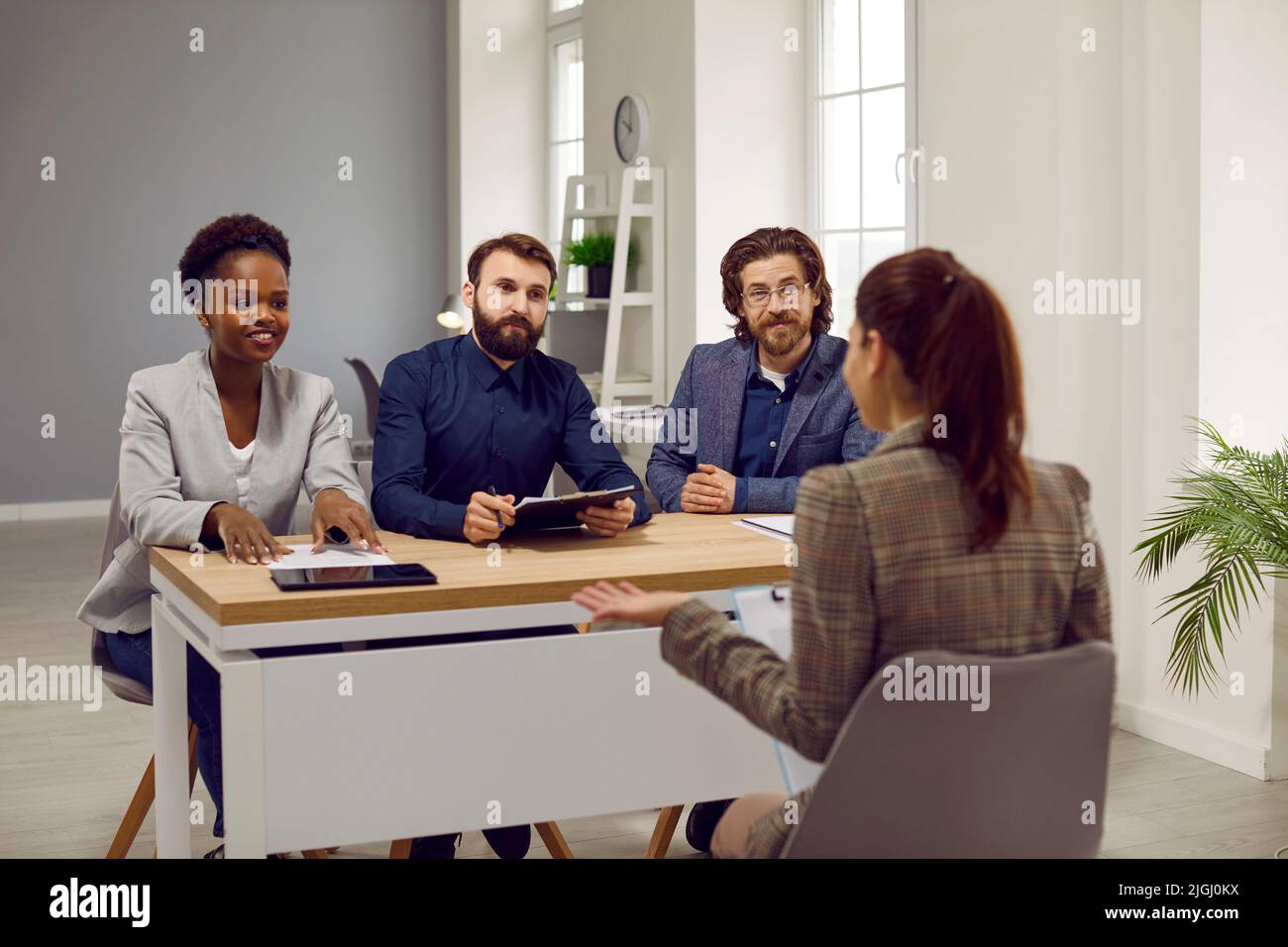 Friendly group of HR employees during interview in office talk to woman ...