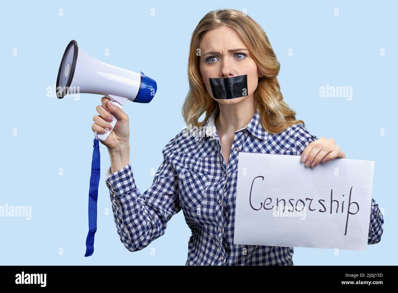 Woman with taped mouth holding megaphone on light blue background ...