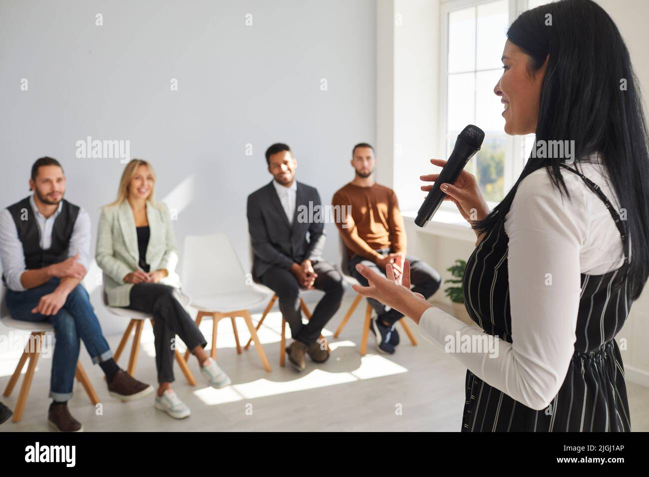 Smiling female coach talk at training with employees Stock Photo - Alamy