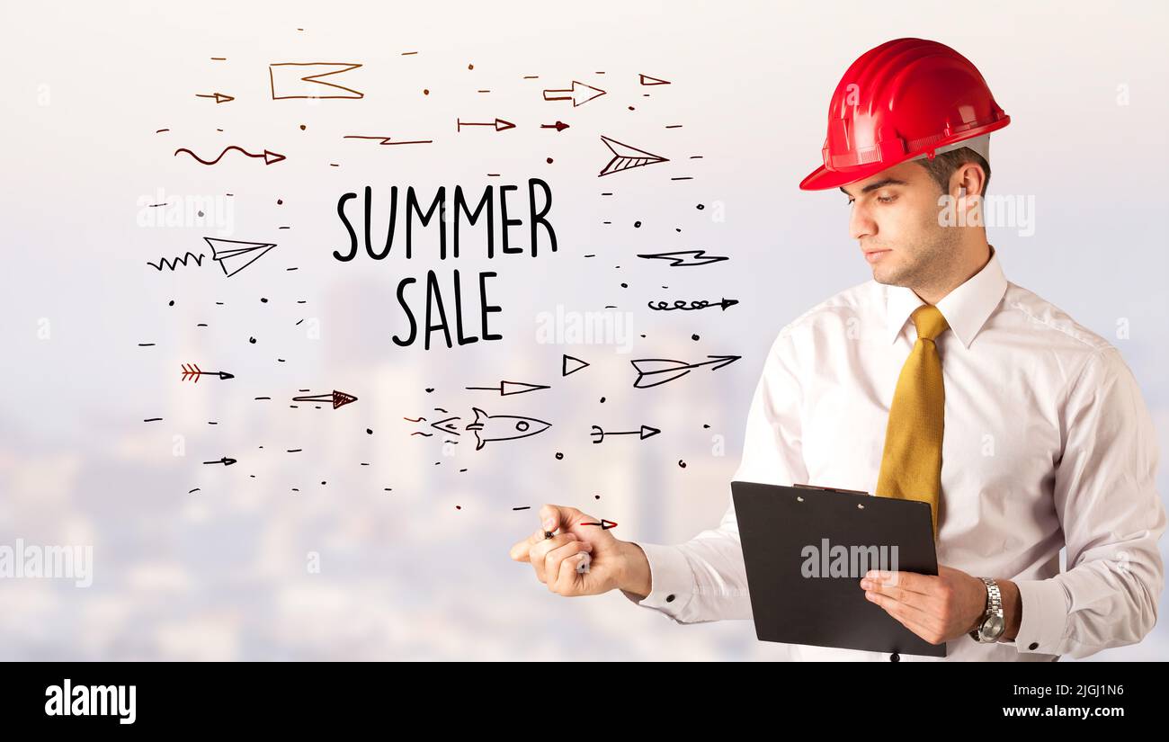 Young businessman with helmet drawing sale sign Stock Photo - Alamy