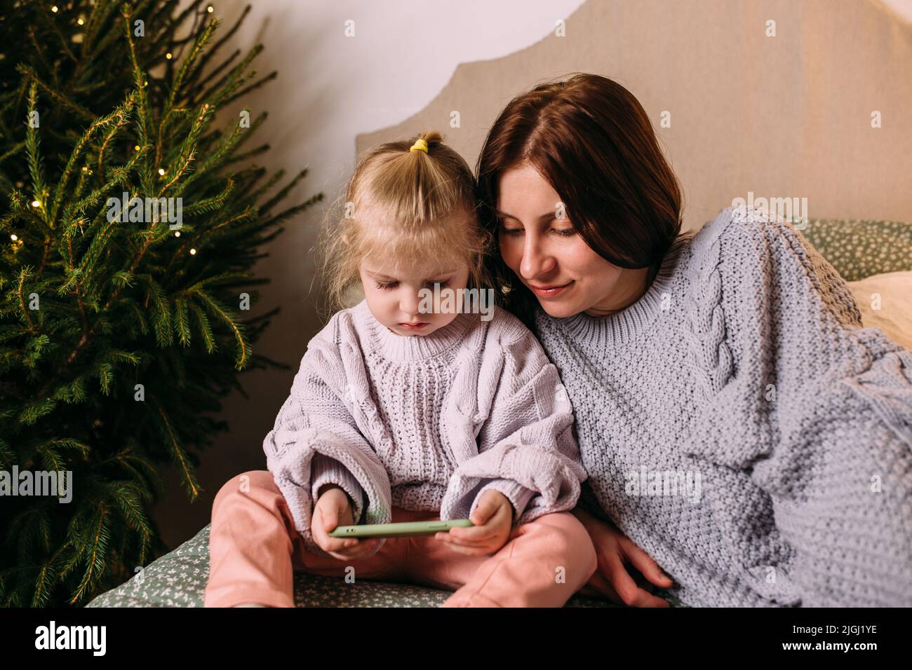 Mom and daughter look at the smartphone at christmas together Stock Photo - Alamy