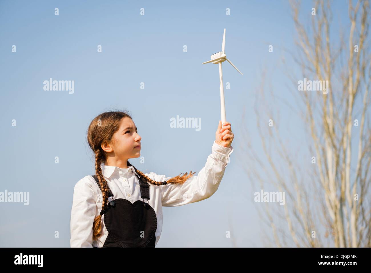 Child playing and looks interested at a wind turbine toy - Concept of ...