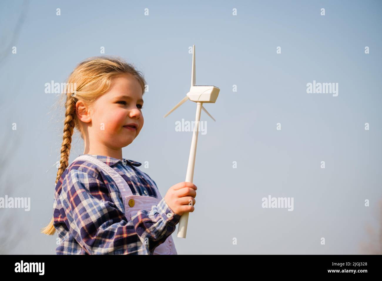Child playing and looks interested at a wind turbine toy - Concept of ...