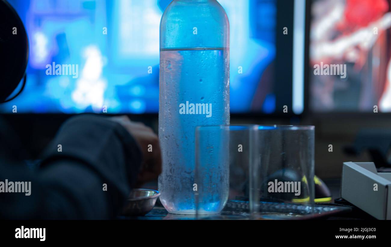 The gamer is busy watching the content of the screen. Has water bottles ...