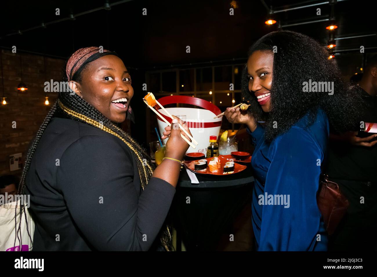 Two African women guests socializing in a sushi restaurant in ...