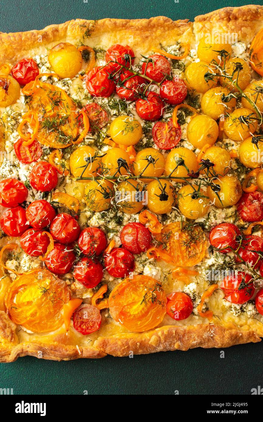 Homemade pie made of puff pastry and yellow, orange and red tomatoes ...
