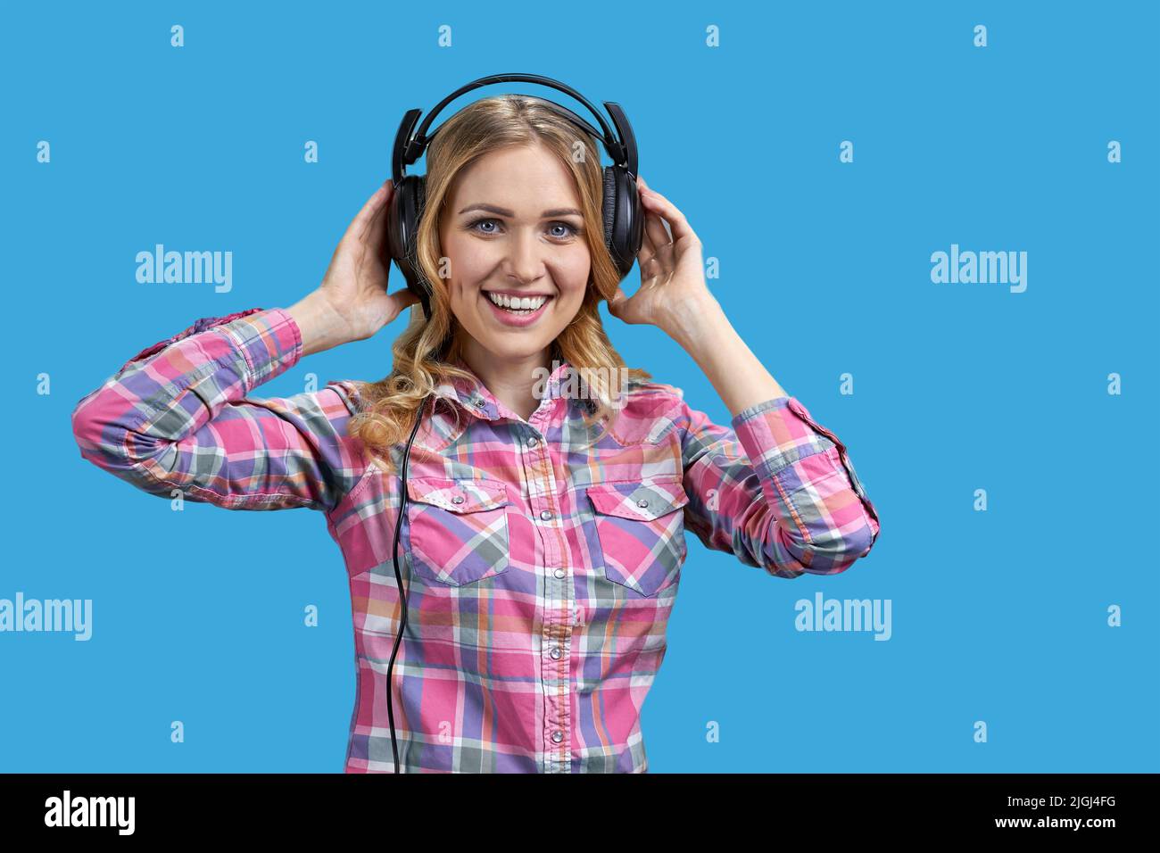 Pretty caucasian woman with headphones looking at camera on color ...