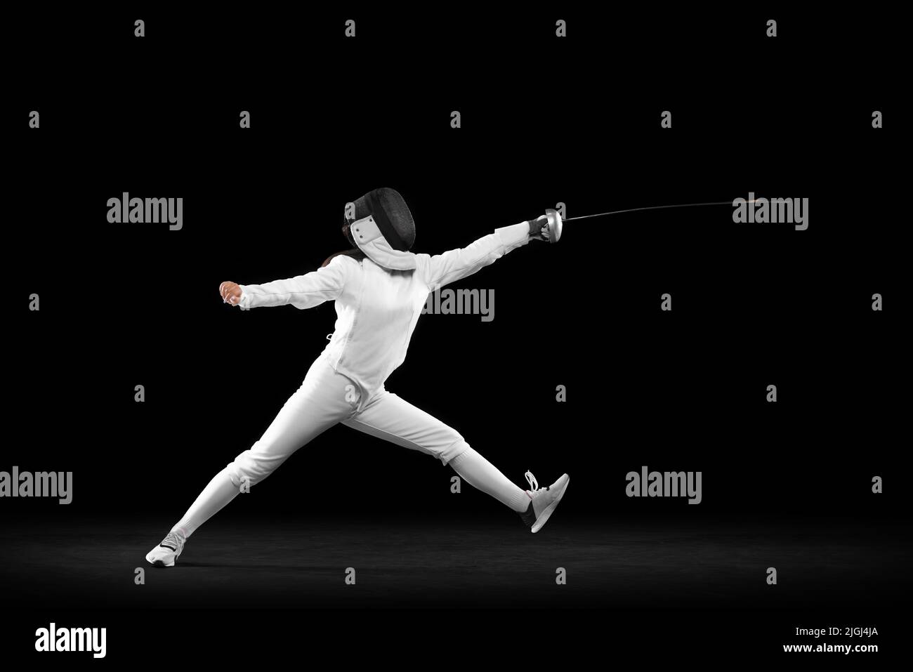 Energetic female fencer in white fencing costume and mask in action ...