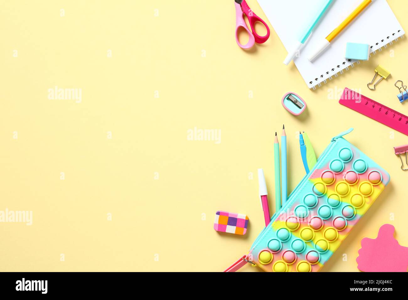 Backpack with colorful school supplies and digital table on yellow ...