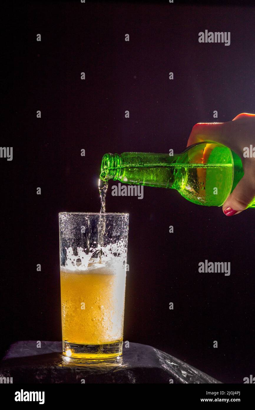With a feminine hand, She poured cold beer with beer bubbles and foam ...